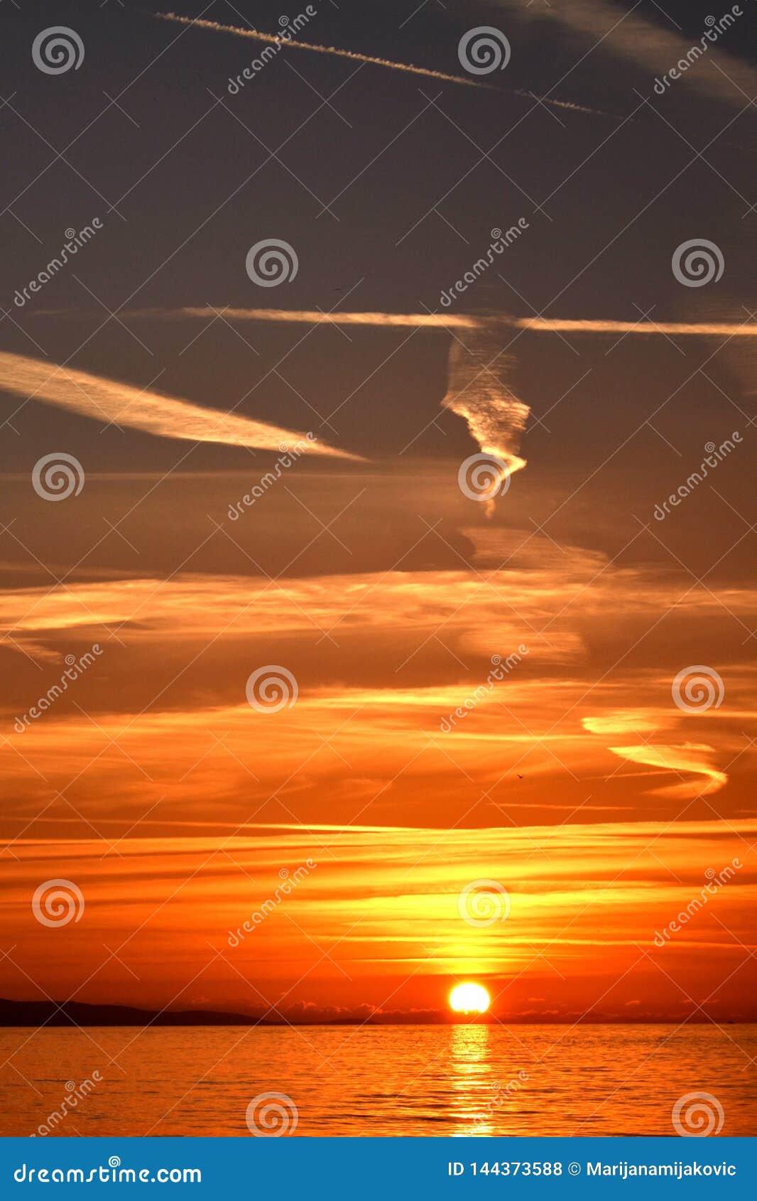 Vertical Sunset Over the Sea with Plane Trails and Clouds Stock Photo ...