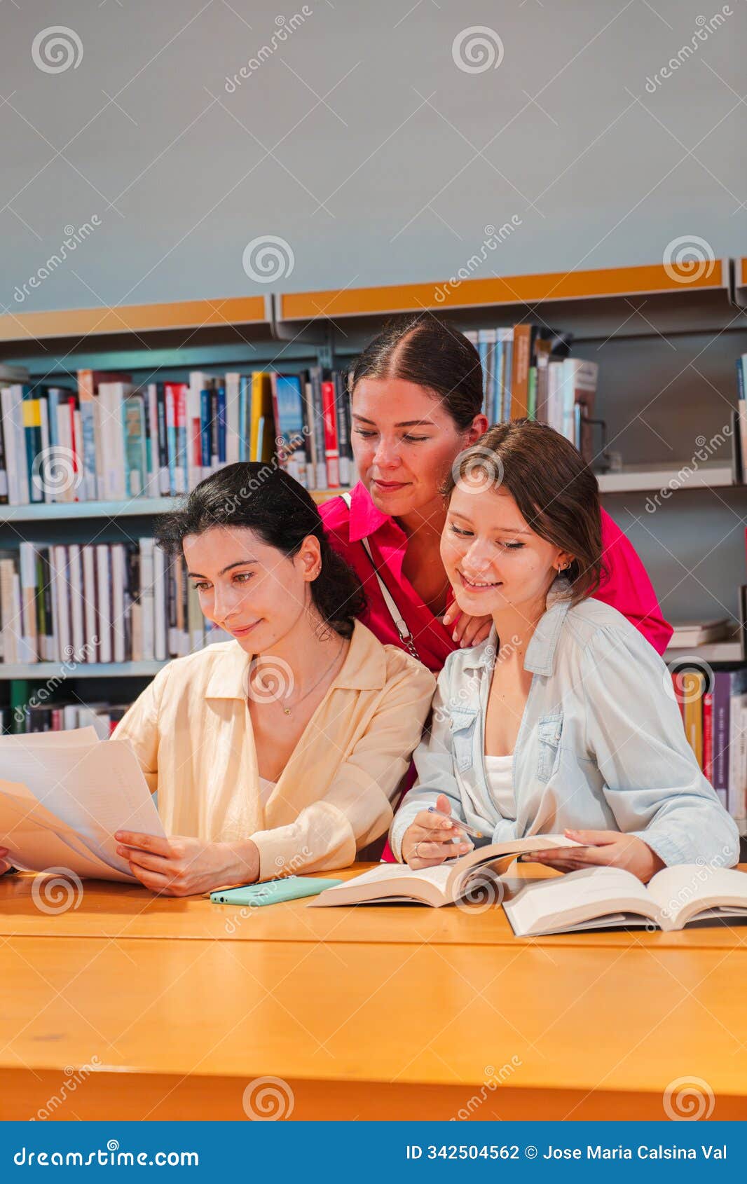 Vertical Three Female Students Studying Together in a Library, Sharing ...