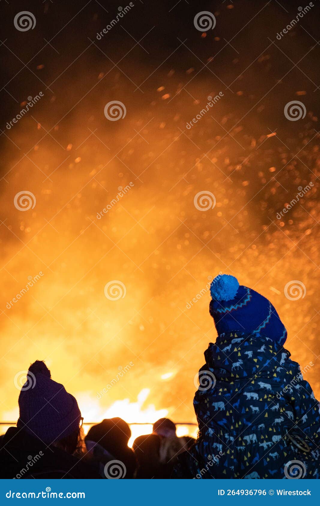 Vertical View of a Child and Crowd before the Roaring Bonfire Flames at ...