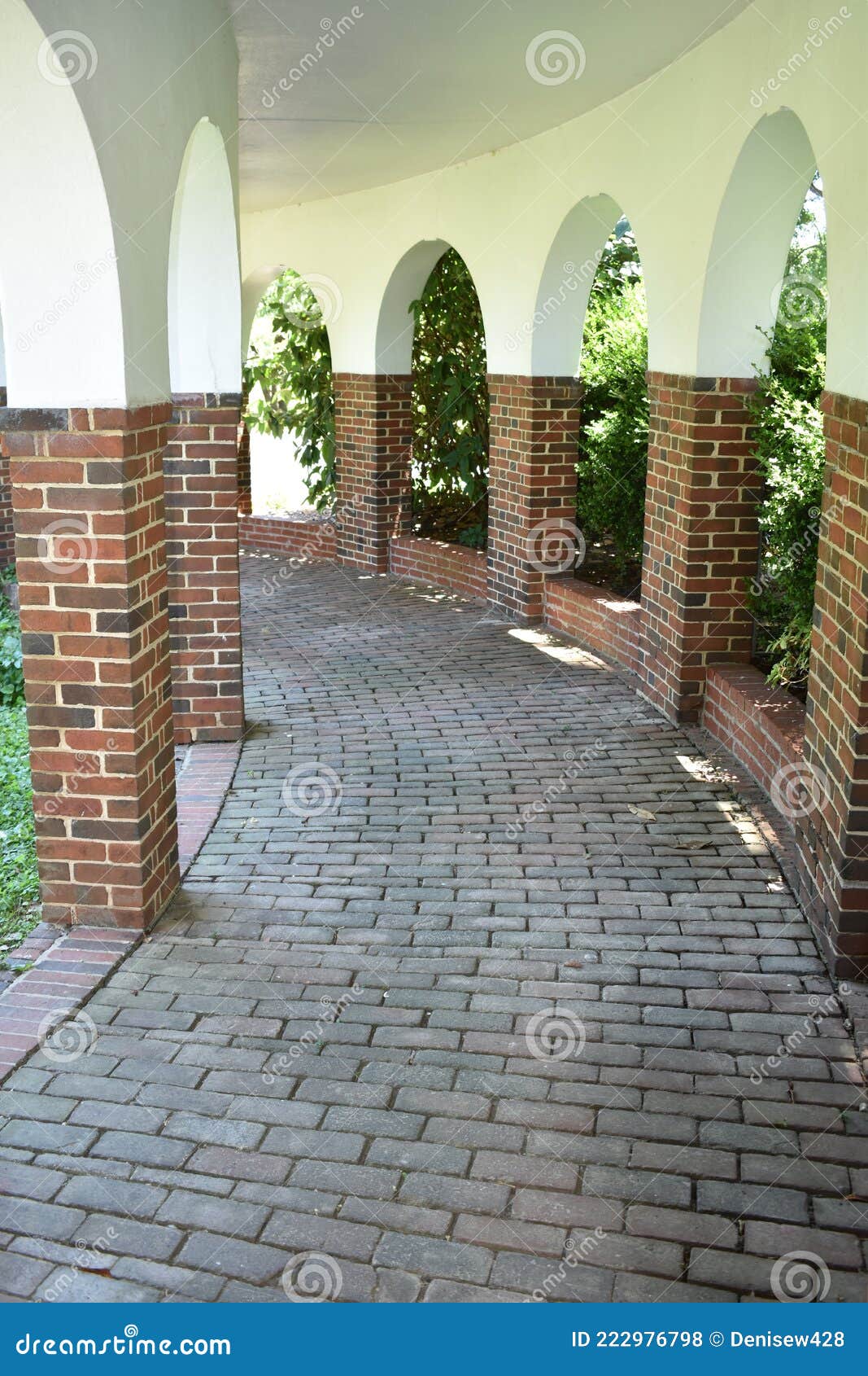 View Down a Curved Walkway with Brick Archways and a White Ceiling ...