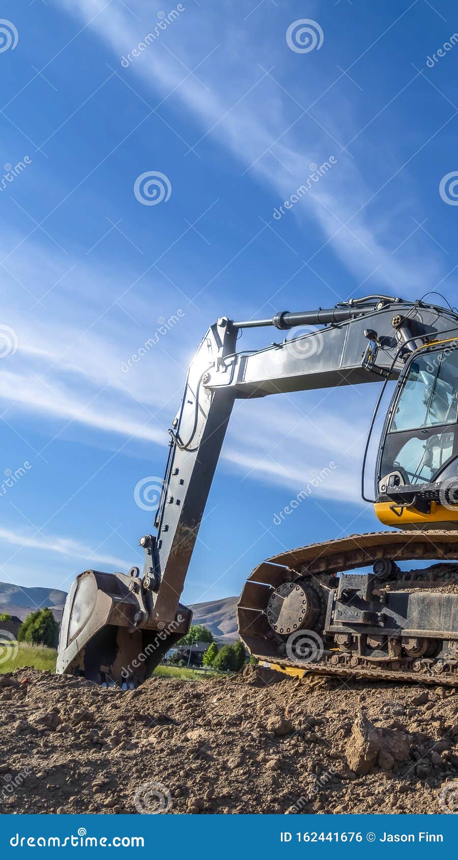 Vertical Yellow Excavator with Continuous Tracks Digging Soil at a ...