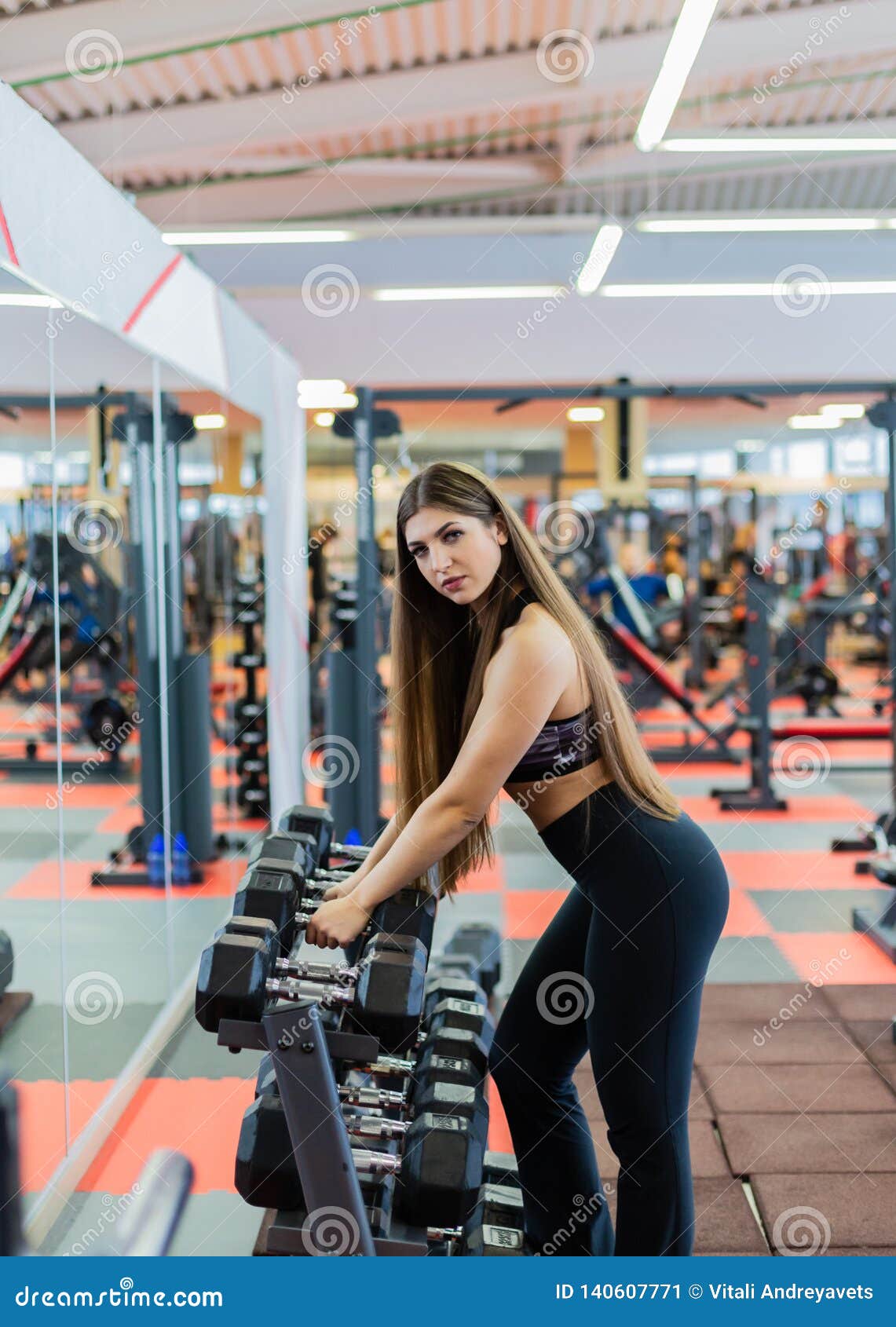 Very Beautiful Girl Takes A Dumbbell From The Racks Stock Image