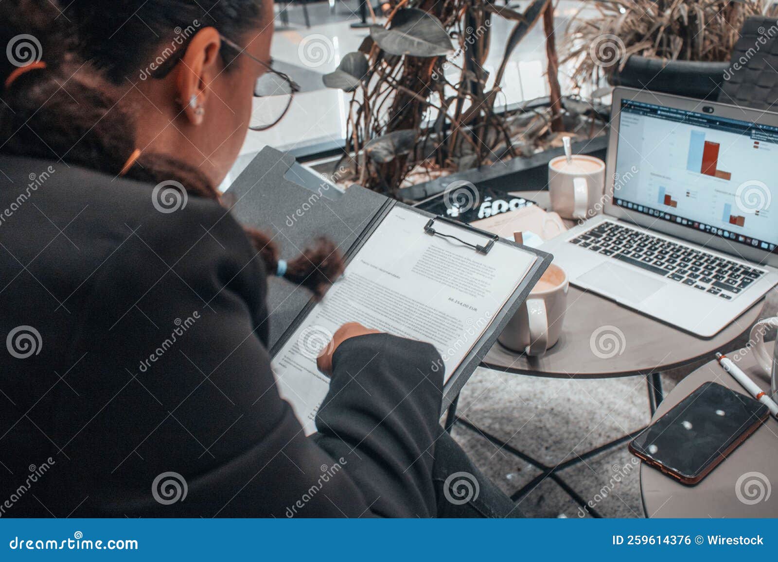 View from Behind of a Female Checking the Business Statistics Using a ...