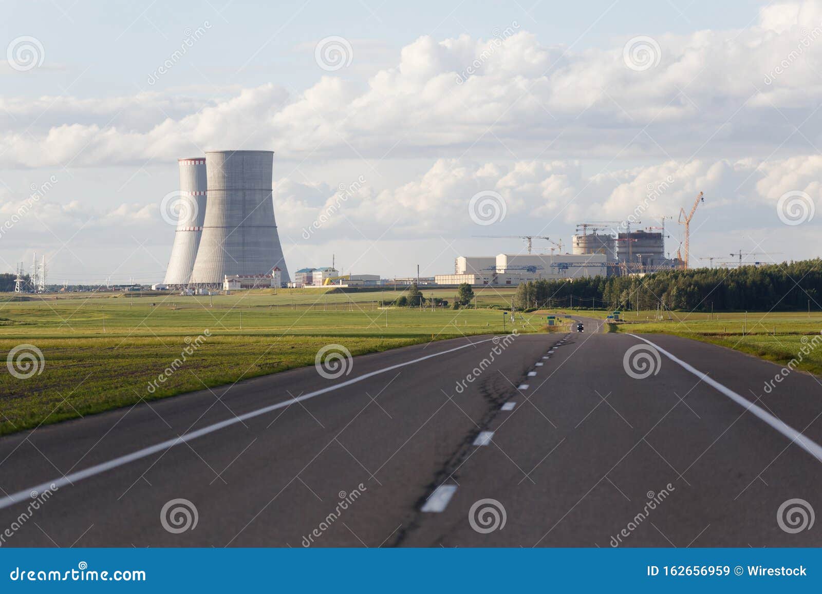 View of an Empty Road in the Middle of a Grassy Field with a Factory in ...