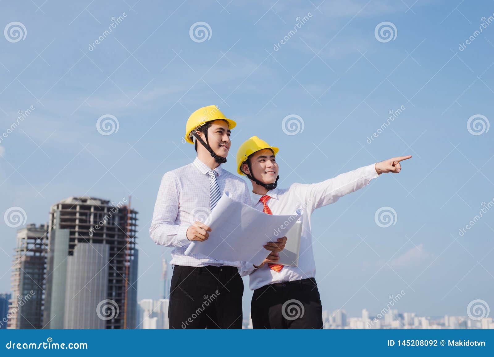View of a Engineer and Worker Watching Blueprint on Construction Site ...
