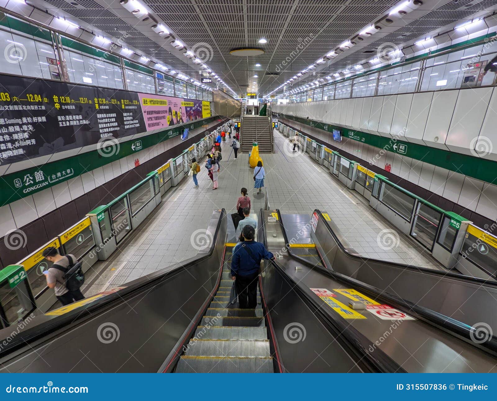 View from an Escalator Towards a Two-way Train Platform with Passengers ...