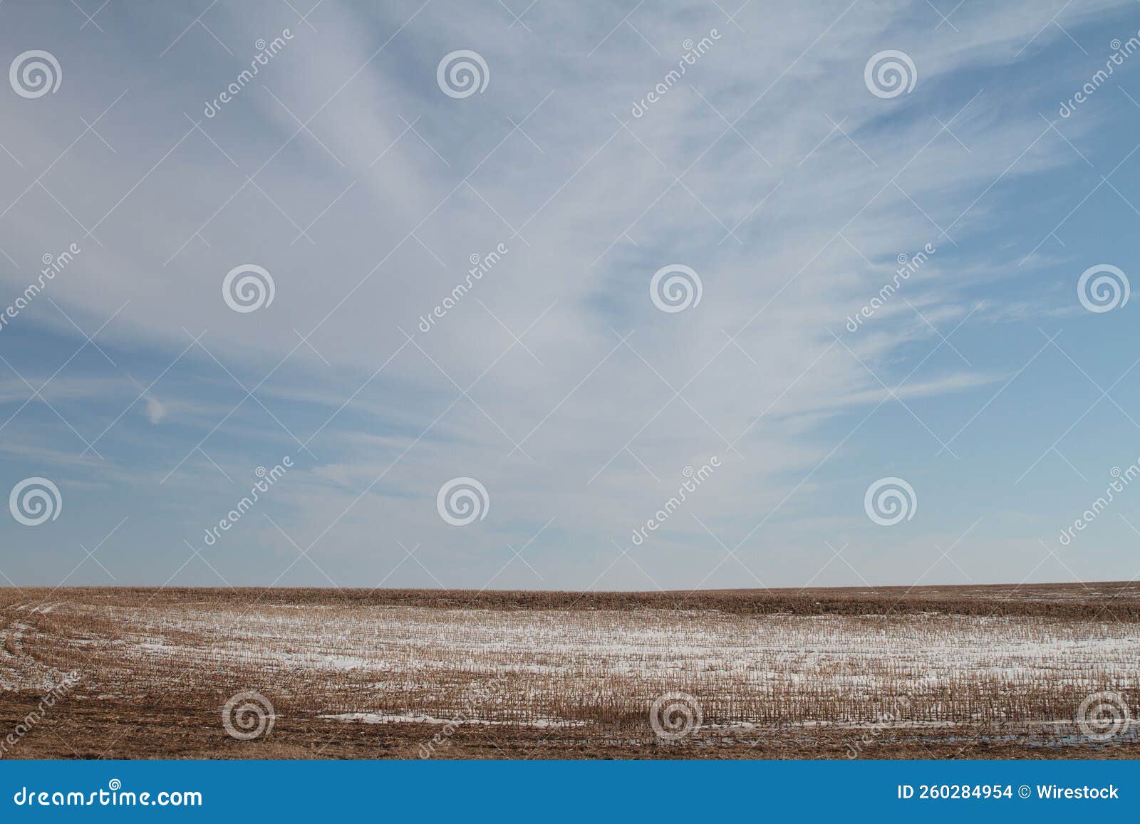 View of a Field with a Layer of Snow Against the Background of the Blue ...