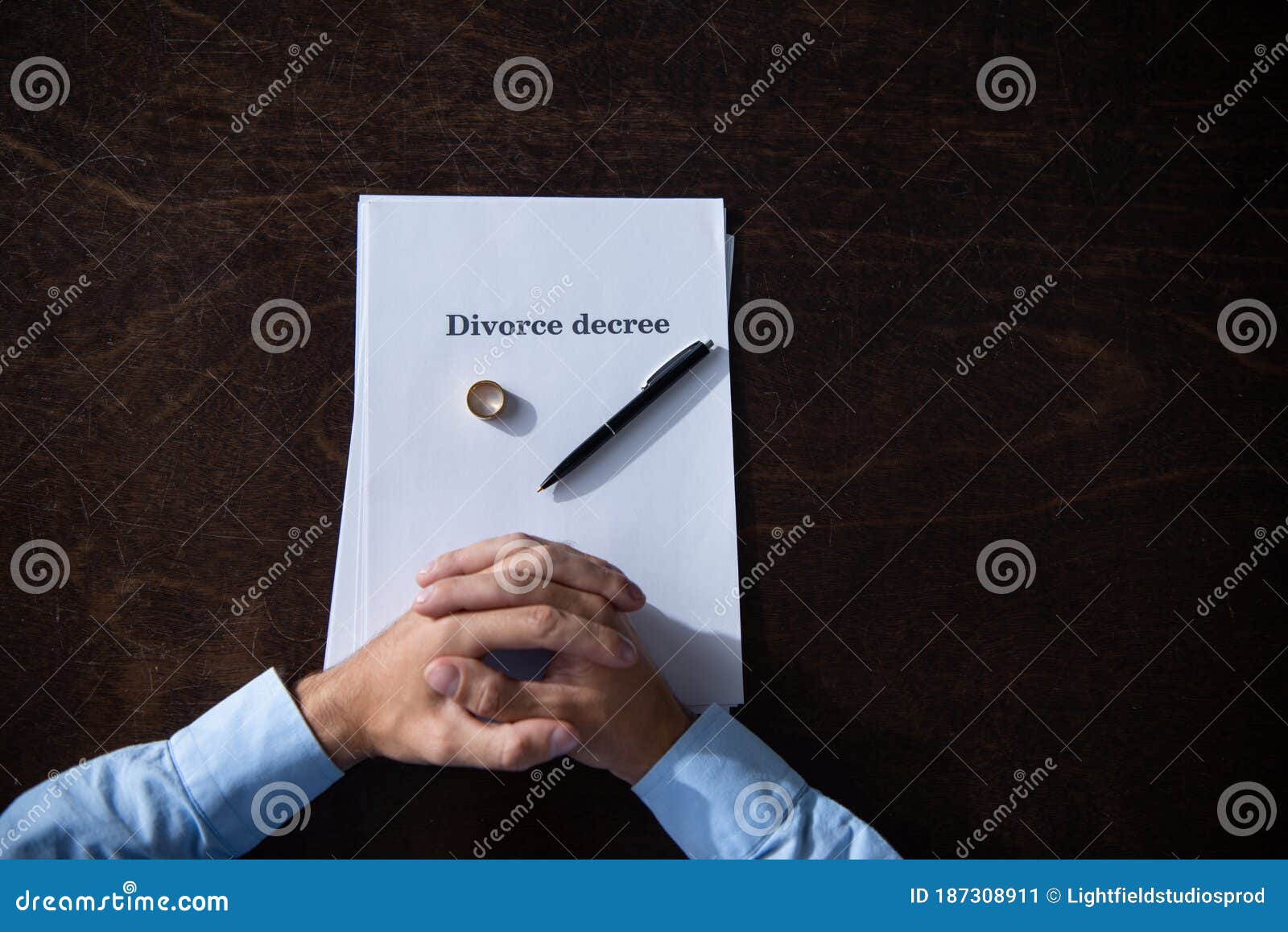 View of Man Sitting at Table with Clenched Hands with Divorce Documents ...