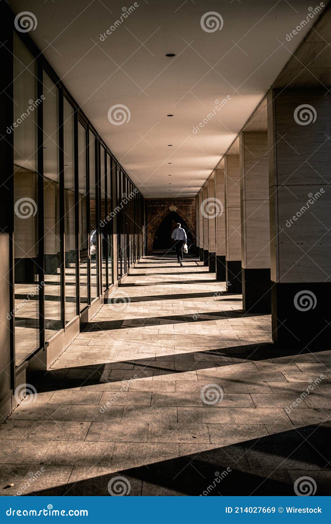 View of a Person Walking in the Hallway with Columns and Mirrors on the ...
