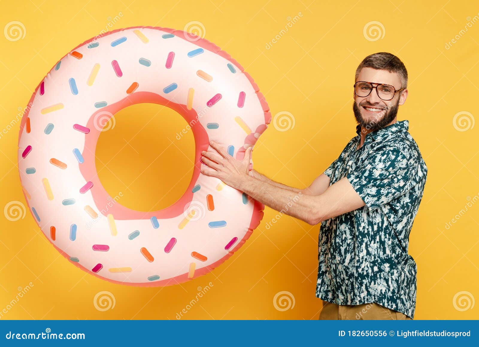 View Of Smiling Bearded Guy In Glasses With Donut Swim Ring On Yellow