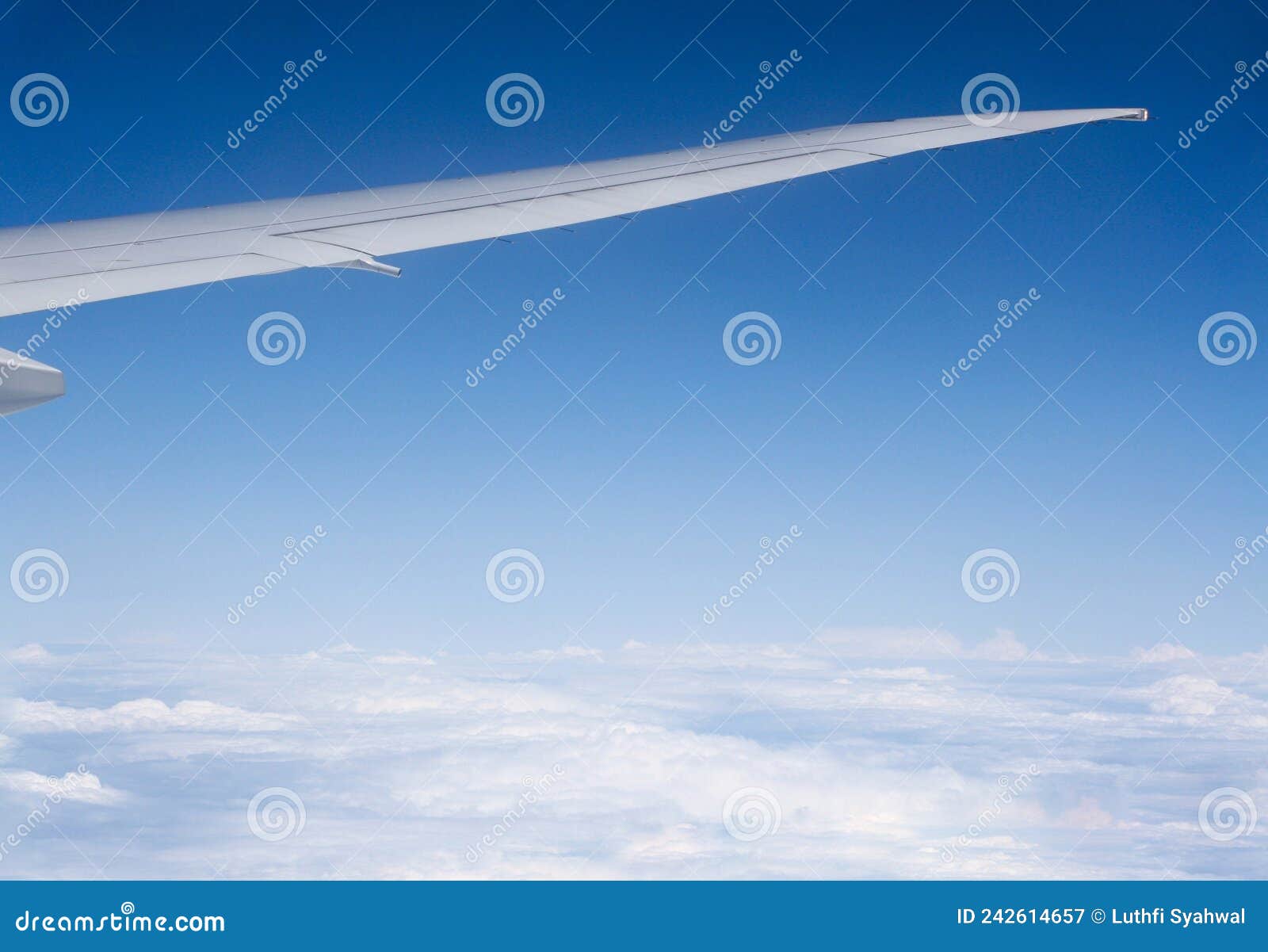 View of Wing of Airplane from Window with Blue Sky Above Clouds ...