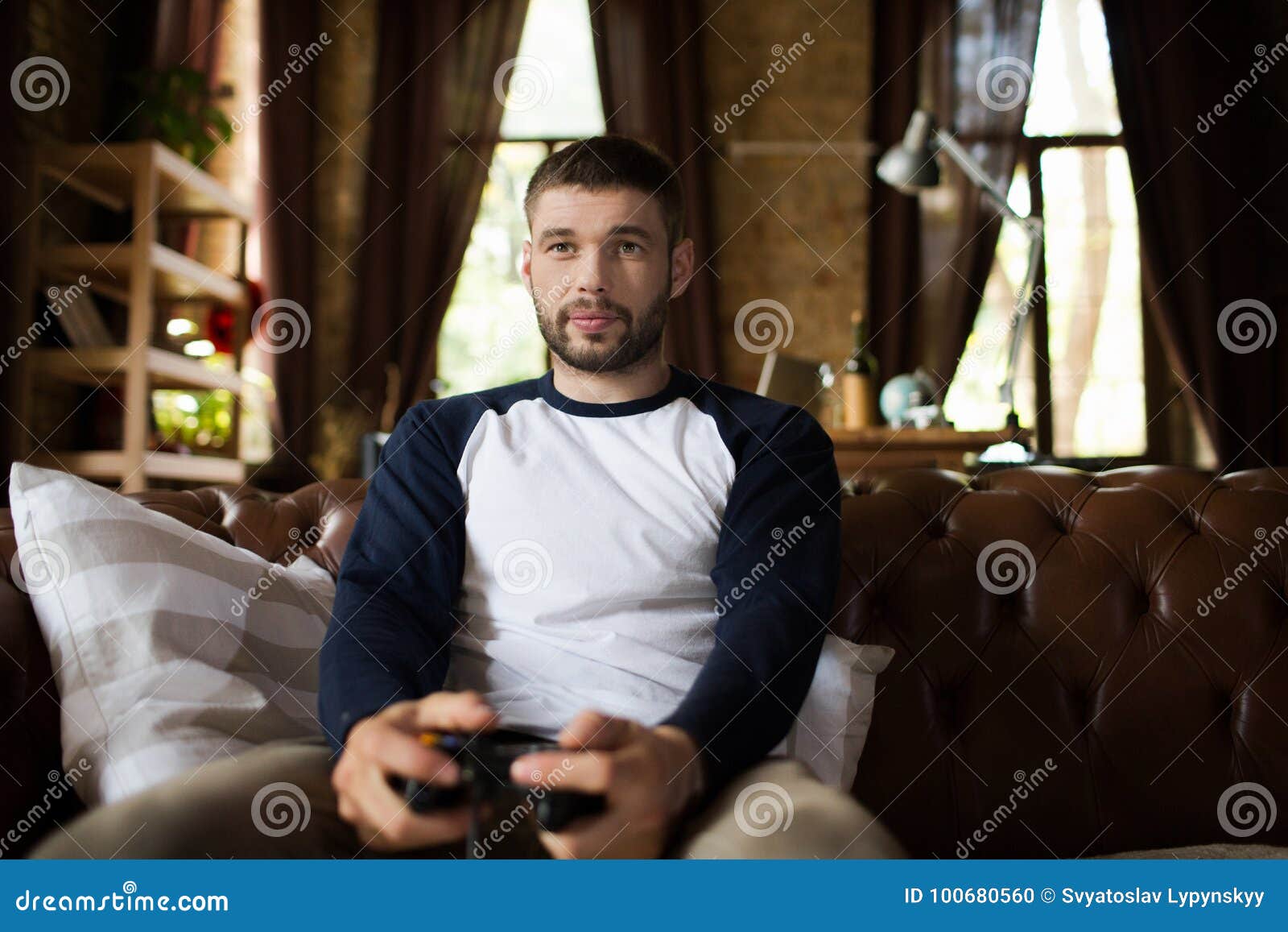 View of Young Man Sitting on Couch Holding Game Controller Joystick ...
