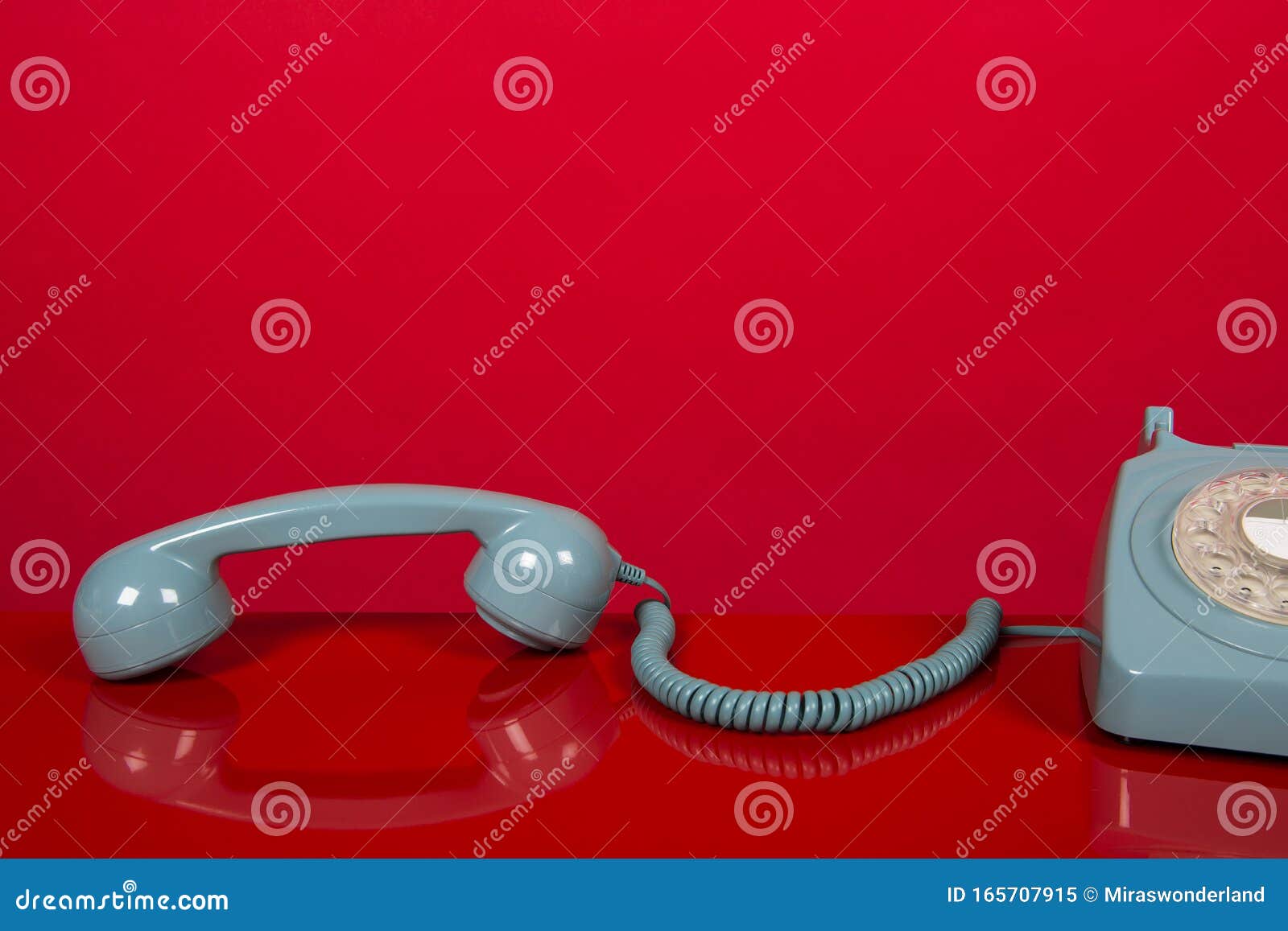 Vintage Blue Dial Phone with the Receiver of the Hook on a Red Modern ...
