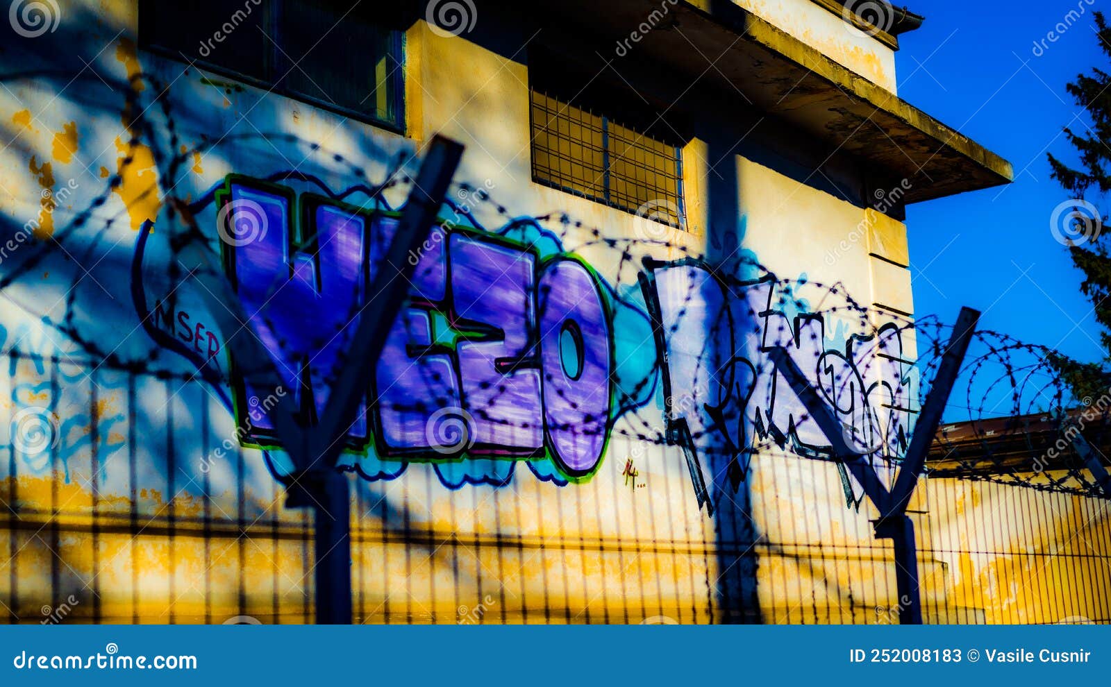 A Violet Graffiti on a Yellow Wall Behind Barbed Wire Editorial Stock ...
