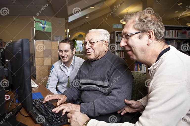 Volunteers Teaching a Senior How To Use a Computer Stock Photo - Image ...