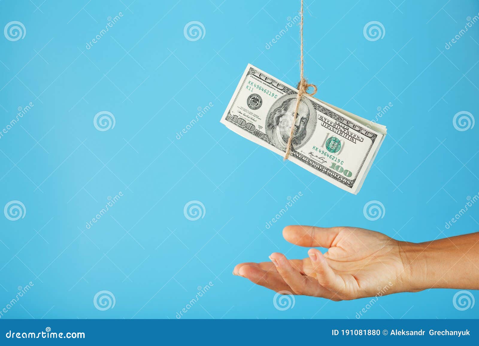 A Wad of Dollars on a String Above a Human Palm on a Blue Background ...