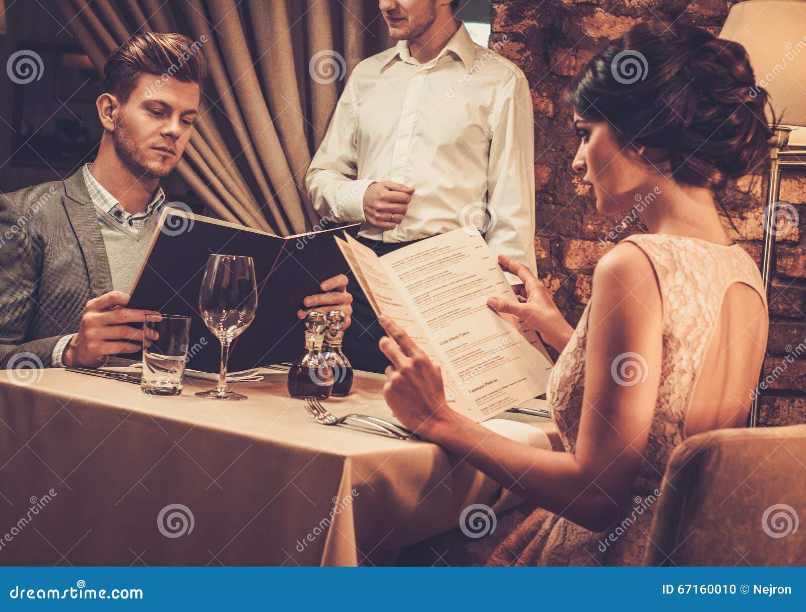 Waiter Explaining the Menu To Wealthy Couple in Restaurant. Stock Photo ...