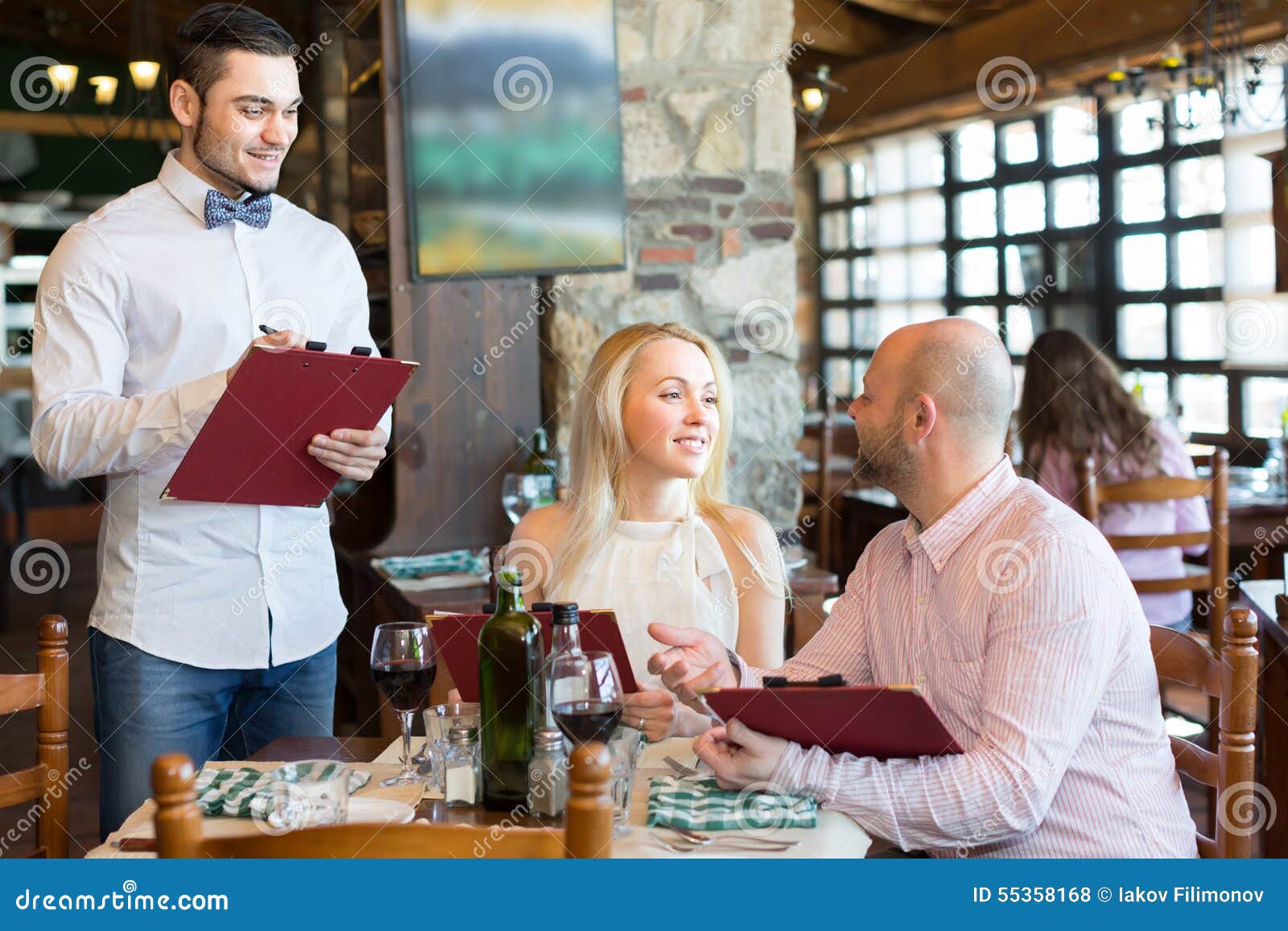 Waiter with Restaurant Guests at Table Stock Photo - Image of ...
