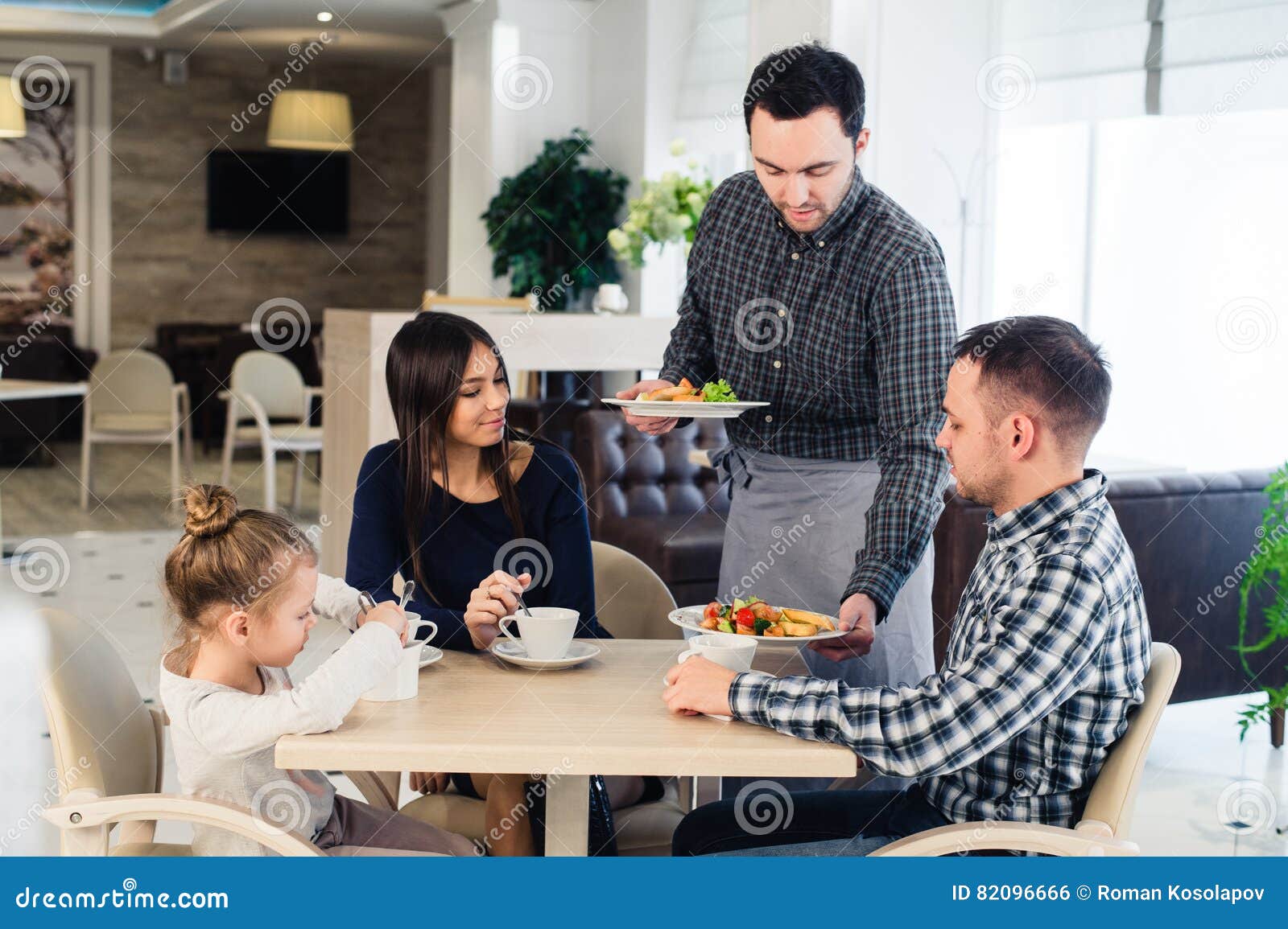 Waiter Serving Family in a Restaurant and Bringing Full Plate Stock ...