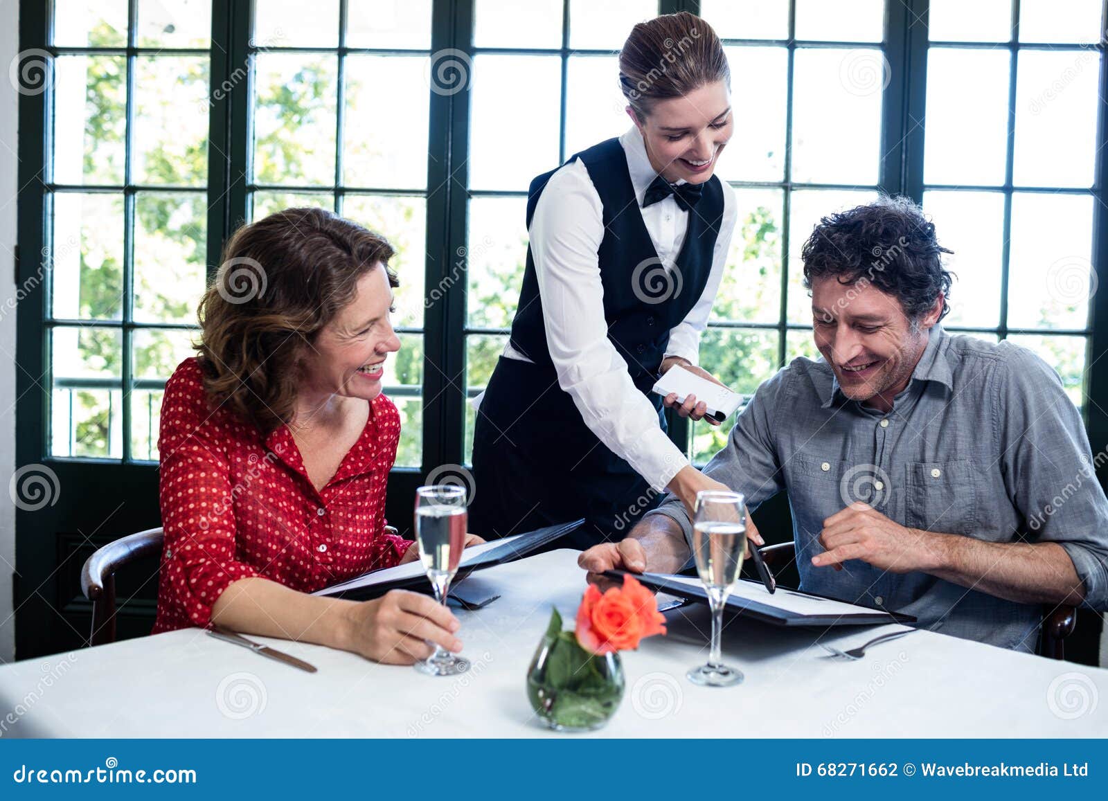 Waitress Assisting a Couple while Selecting Menu Stock Photo - Image of ...