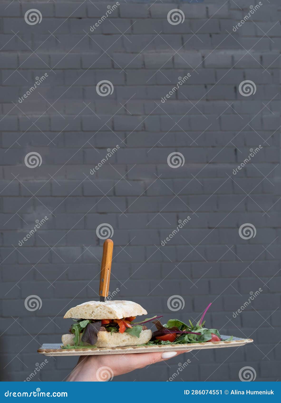 Waitress Hand Holding a Burger with Meat on Brik Wall Background Stock ...