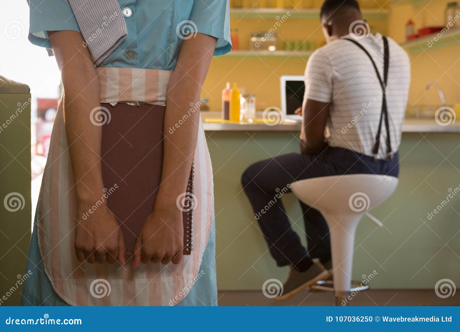 Waitress Holding Menu while Man Using Laptop Stock Photo - Image of ...