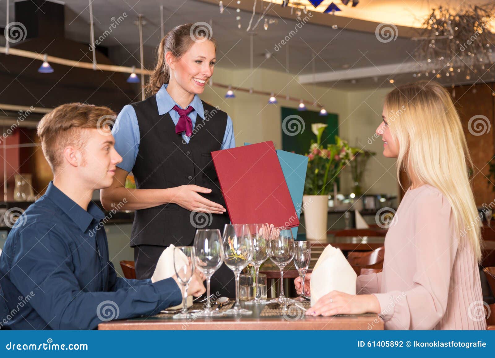 Waitress in Restaurant Presenting the Menu To Two Guests Stock Photo ...