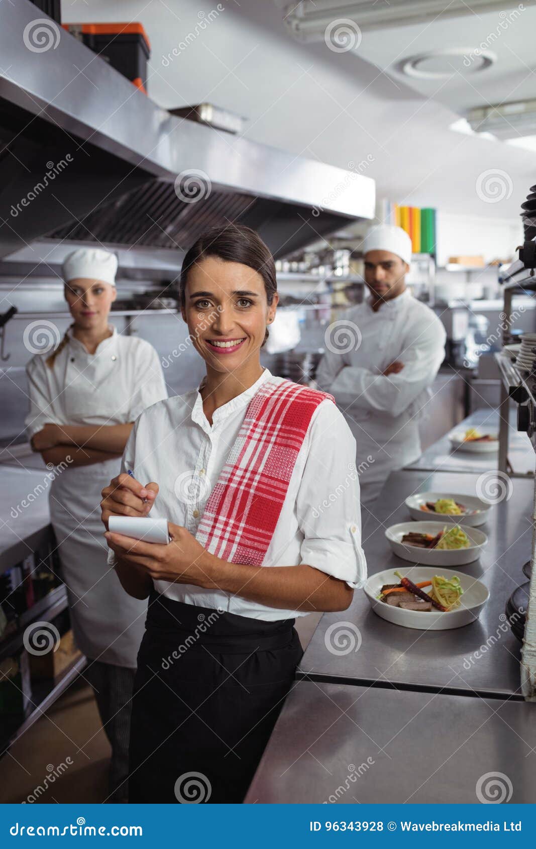 Waitress Standing with Kitchen Staff in Commercial Kitchen Stock Photo ...