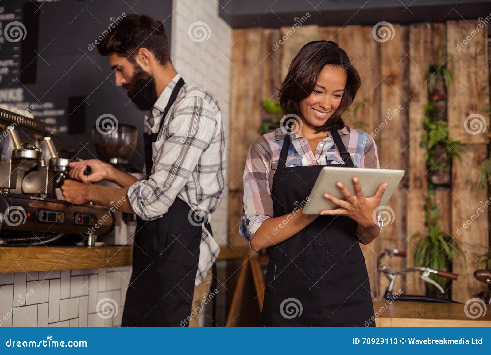 Waitress Using Digital Tablet while Waiter Preparing Coffee in ...