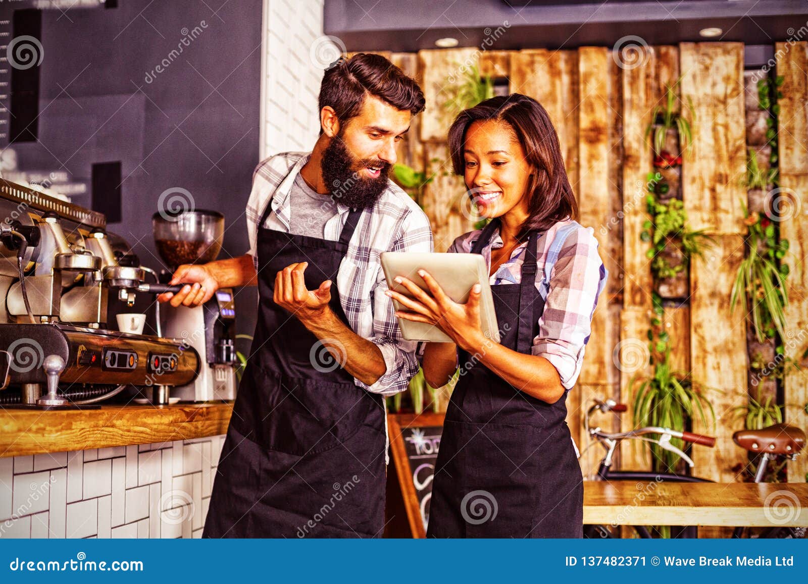 Waitress Using a Tablet Computer and Waiter with Coffee Machine Stock ...