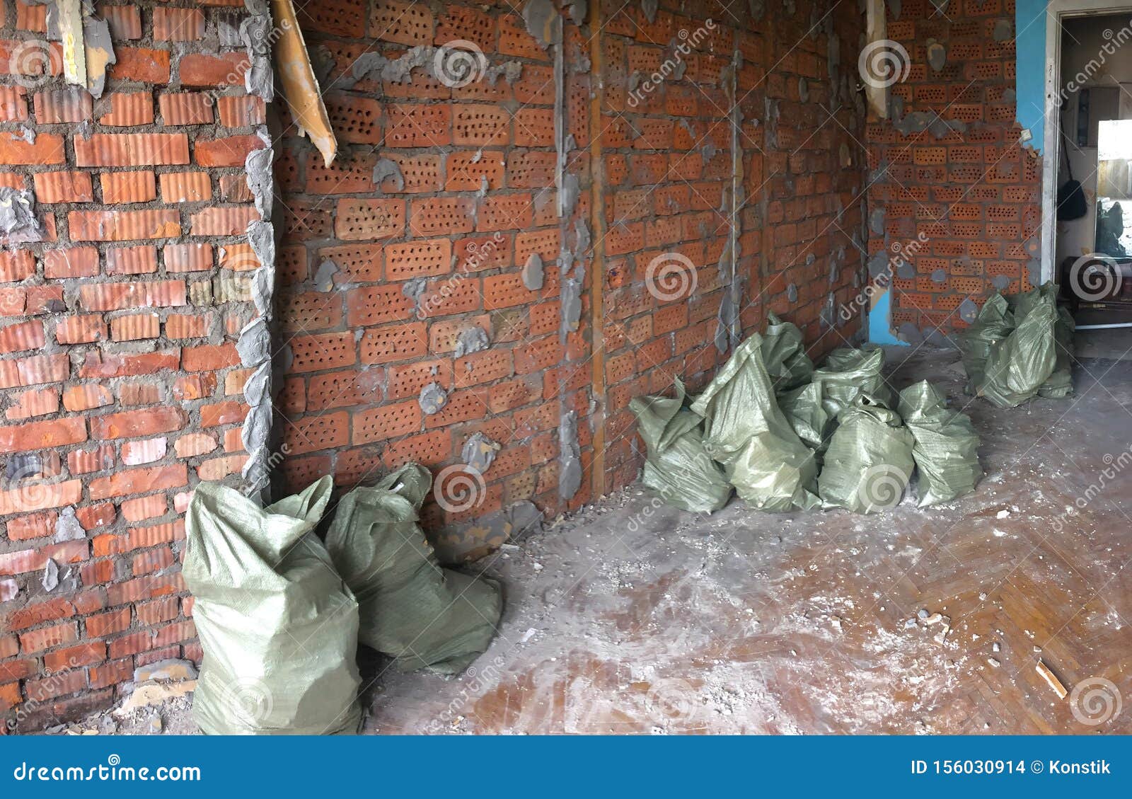 Wall with a Layer of Plaster Removed and Bags of Construction Waste ...