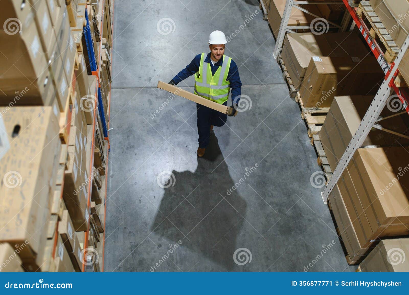 Warehouse Worker in Blue Uniform Holding a Large Cardboard Box. Stacks ...