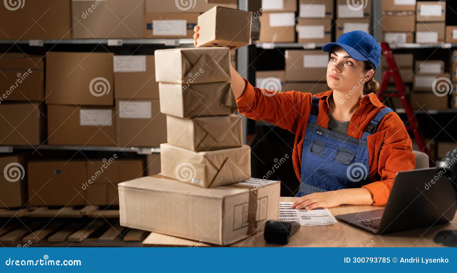 Warehouse Worker Sorts Parcels while Working Using Laptop Computer in ...