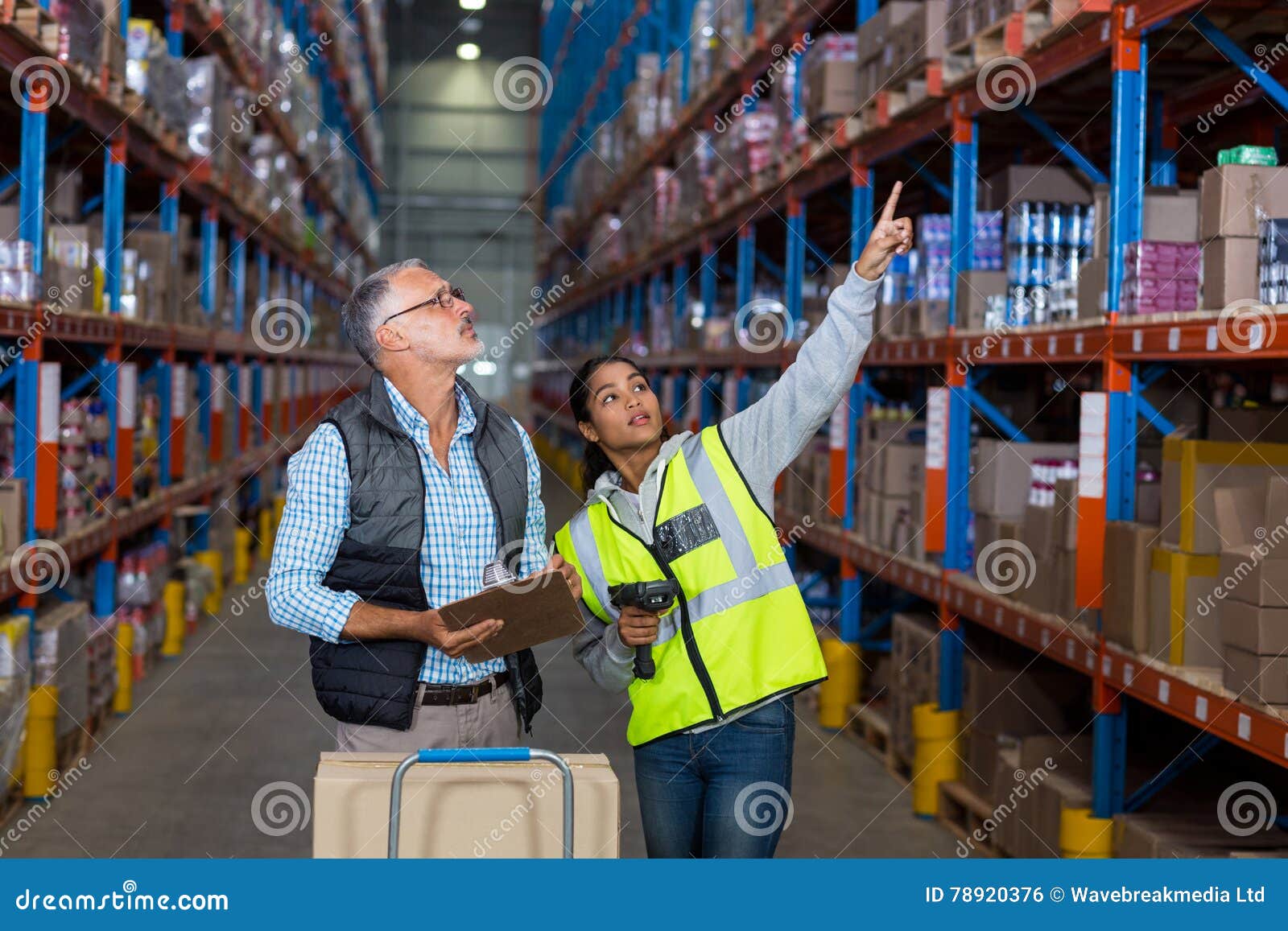 Warehouse Workers In Safety Uniform Working In Warehouse Full Of Tall ... Warehouse Workers In Safety Uniform Working In Warehouse Full Of Tall ...