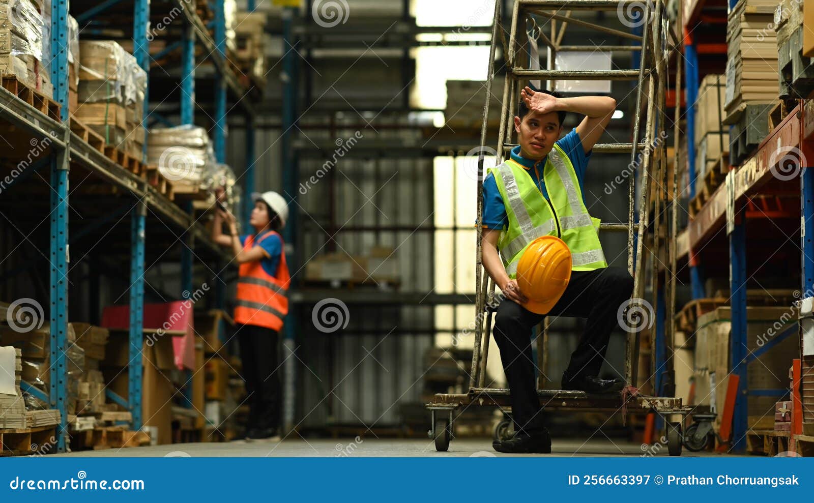 Warehouse Workers In Safety Uniform Working In Warehouse Full Of Tall ... Warehouse Workers In Safety Uniform Working In Warehouse Full Of Tall ...