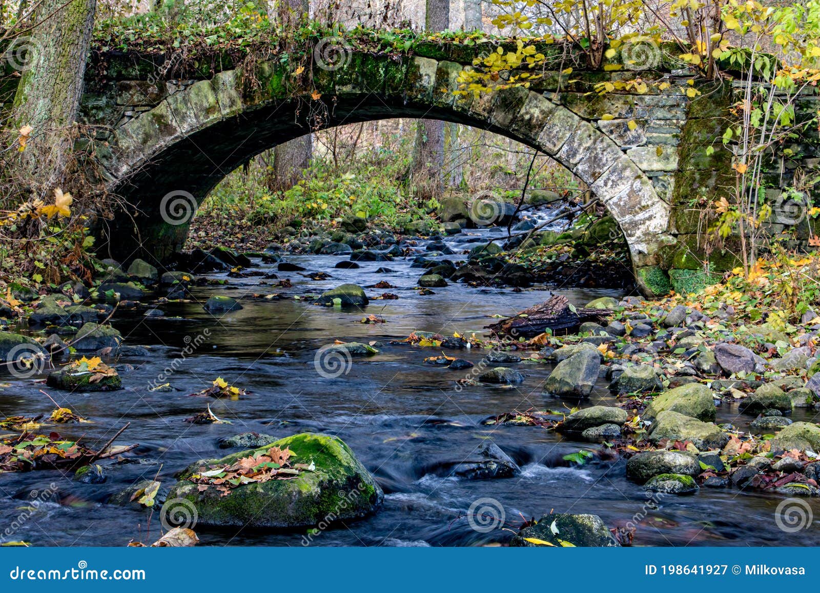 A Water Cascade in the Creek Flowing Under an Ancient Stone Bridge ...
