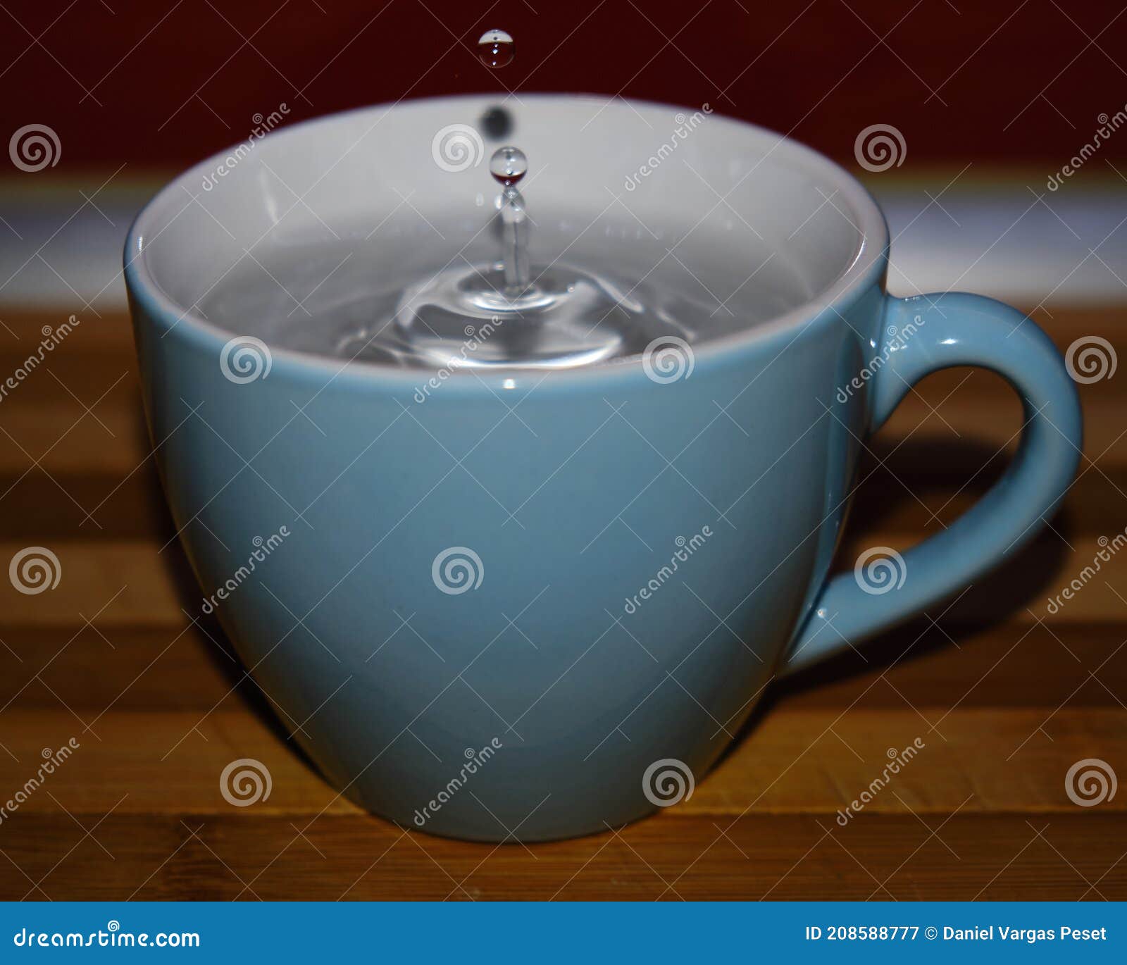 Water Drop Falling into a Blue Mug Over a Red Background Stock Image ...