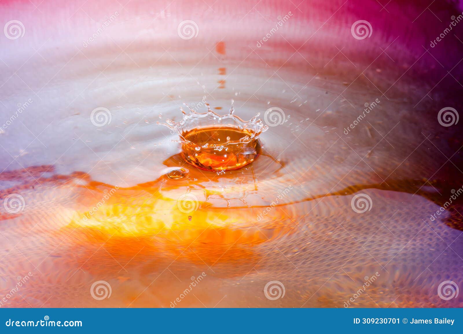 Water Droplet Causes a Splash in Multi-coloured Water Creating a Water ...