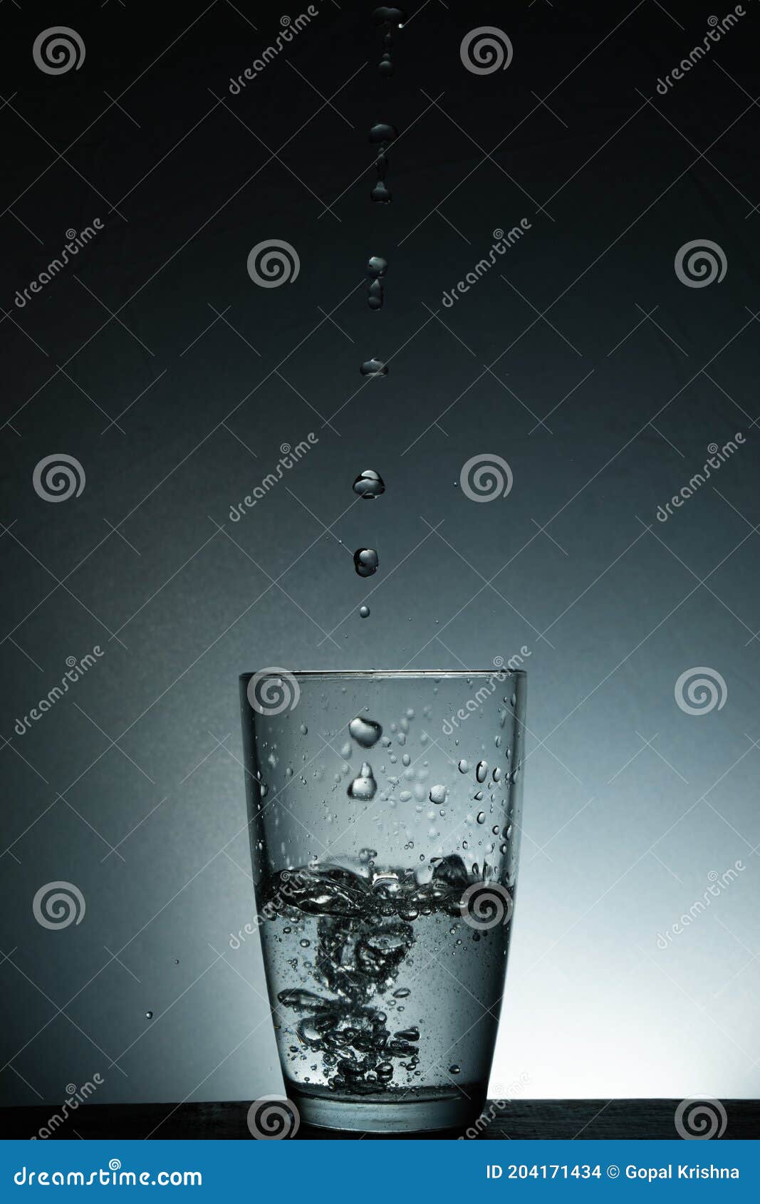 Water Drops into a Half Glass of Water in it Stock Photo - Image of ...