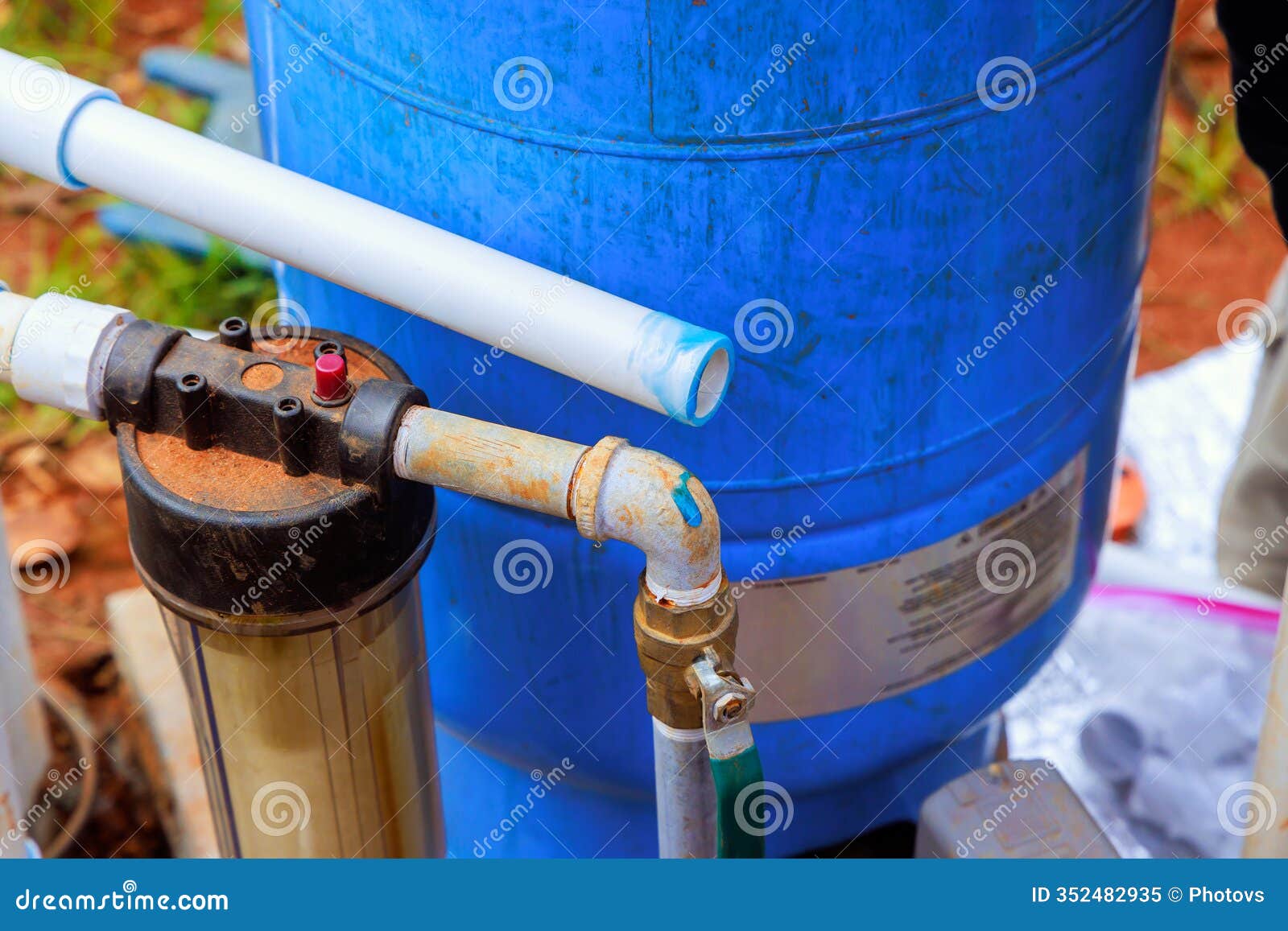 Water Filtration Setup with Blue Barrel and Interconnected Pipes in an ...