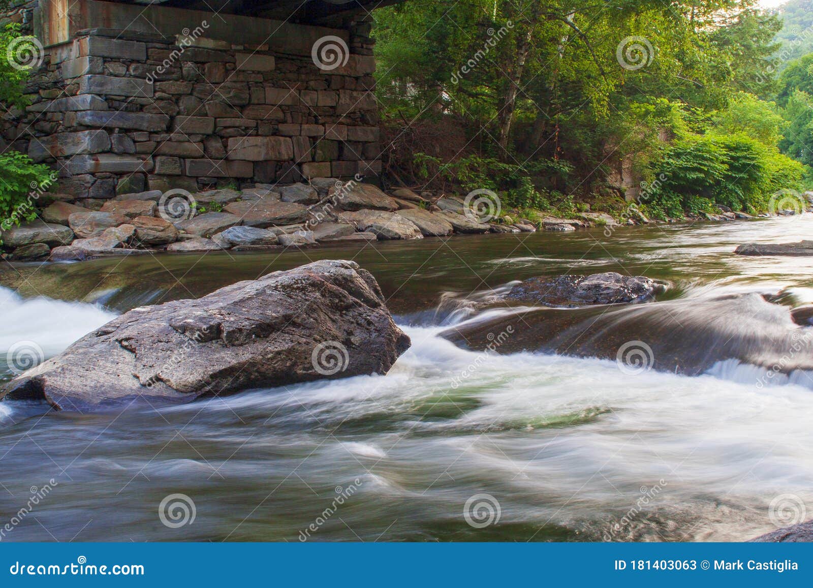 Water Flowing Over Rocks with Old Stacked Stone Wall in Background ...