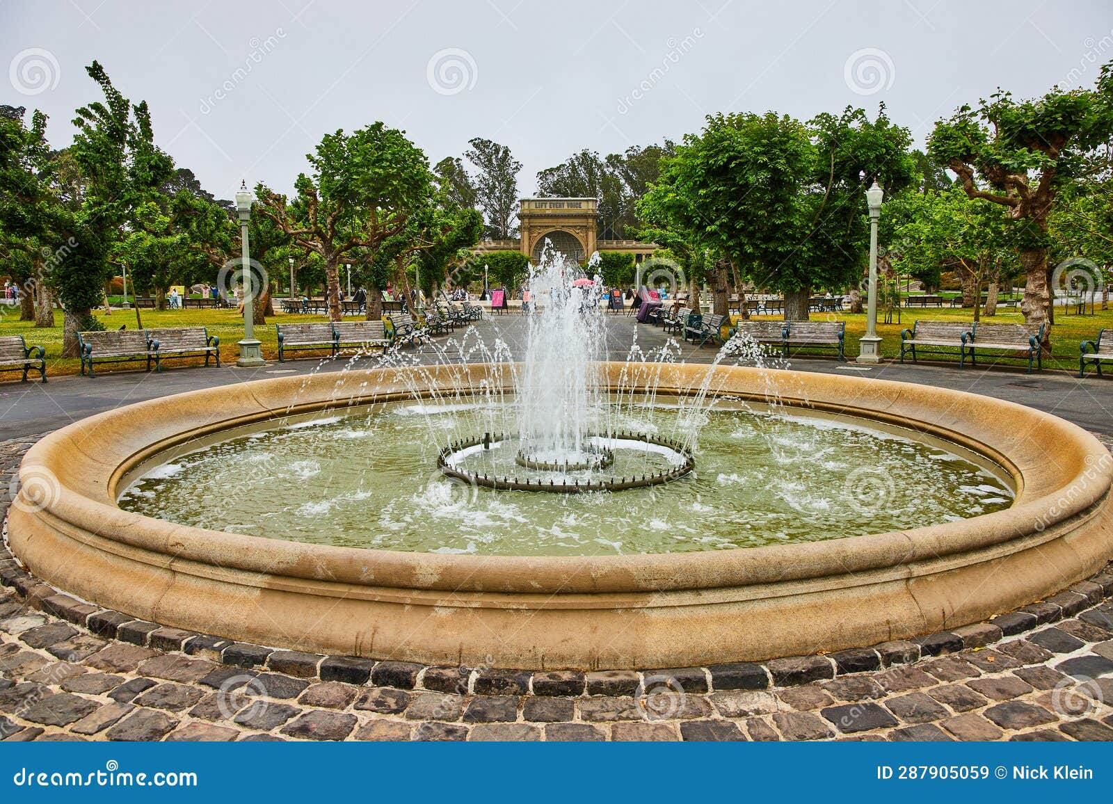 Water Fountain with Benches Around Circular Pathway and Park in ...