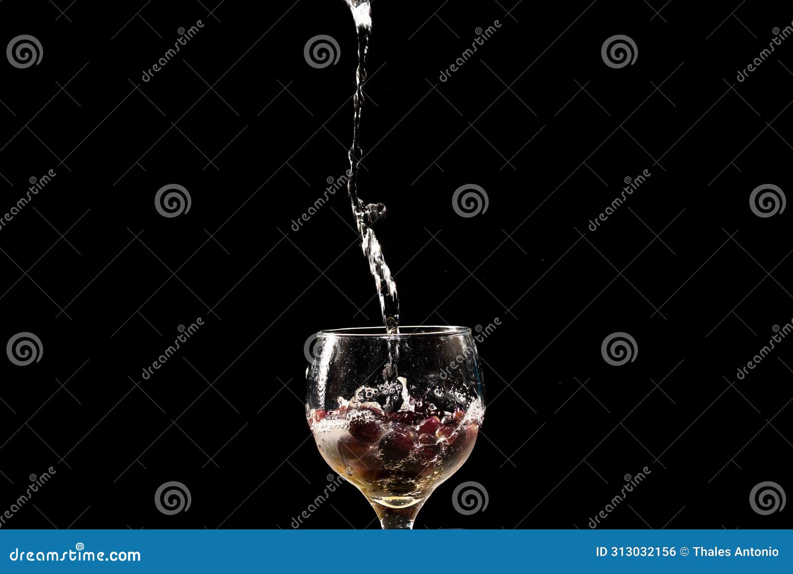Water in Streams and Drops Falling into a Wine Glass with Grapes Inside ...