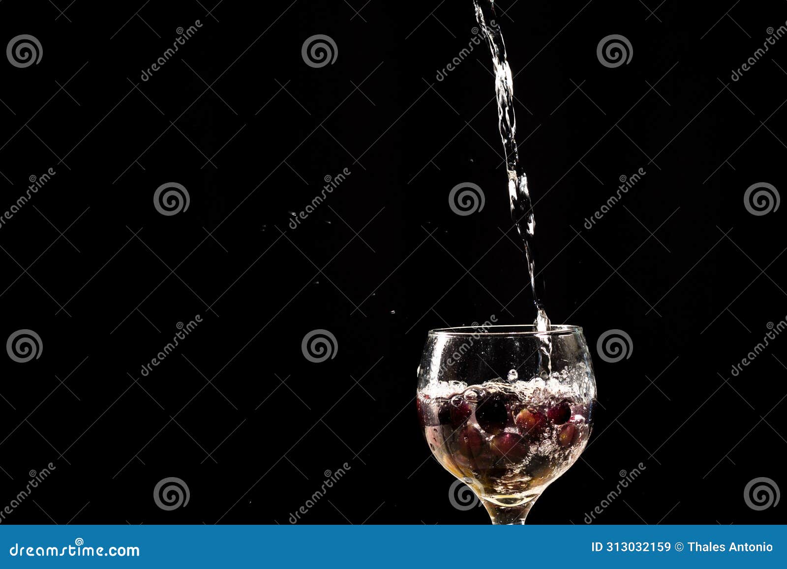 Water in Streams and Drops Falling into a Wine Glass with Grapes Inside ...