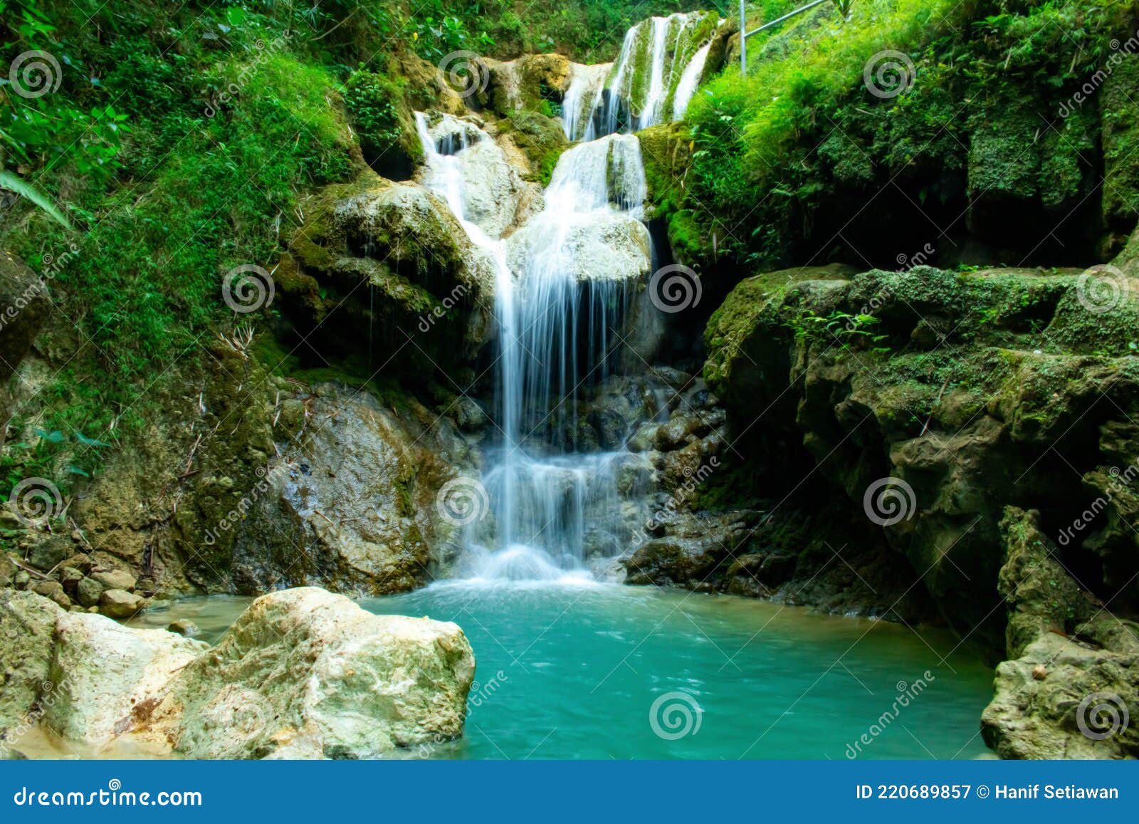 A Waterfall Flowing Over Rocks into a River or Lake with Turquoise ...