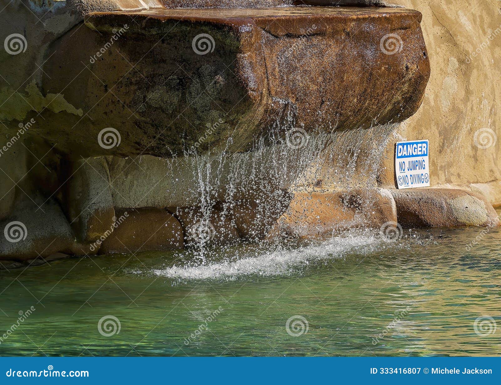 A Waterfall at a Resort Swimming Pool with a Warning Sign Stock Image ...