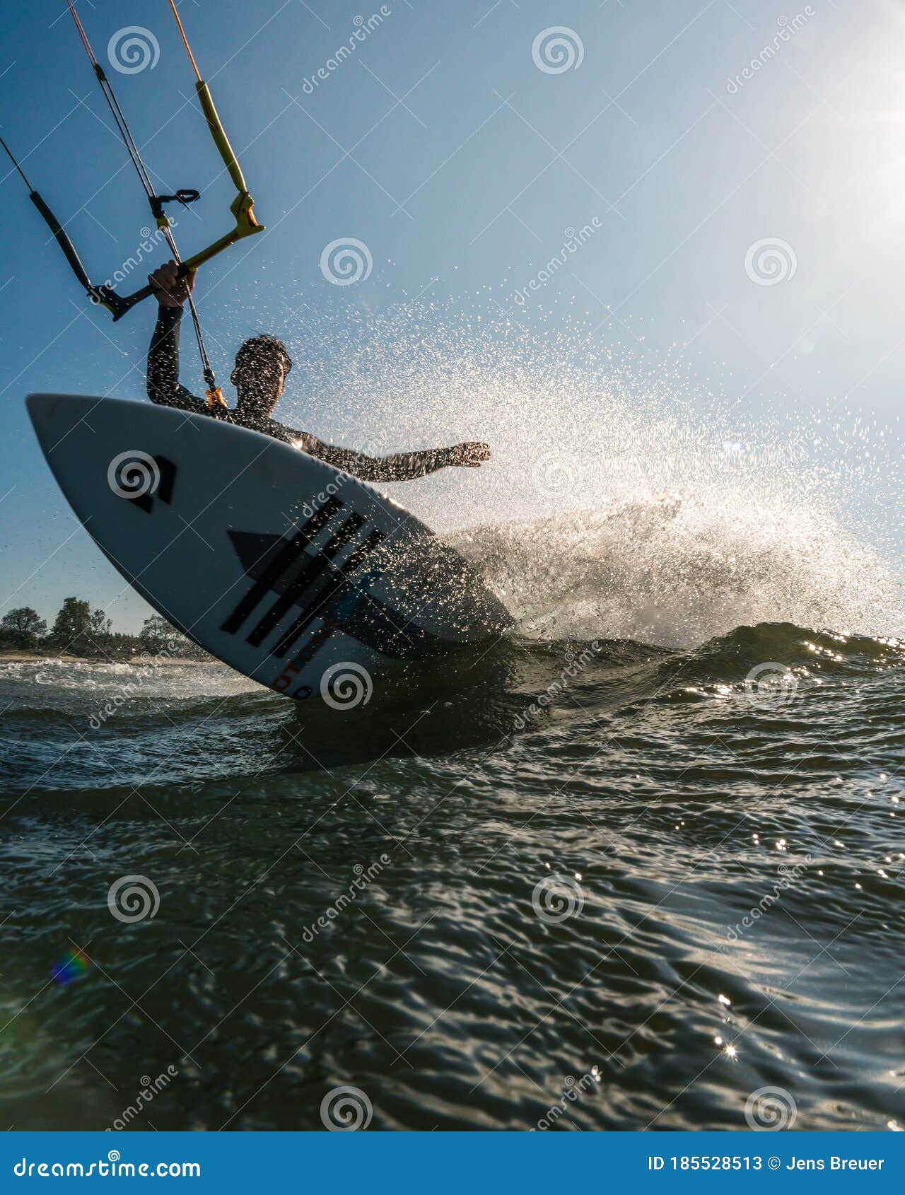 Wave Kitesurfer Doing a Turn in a Wave and Splashing Water is Backlit ...