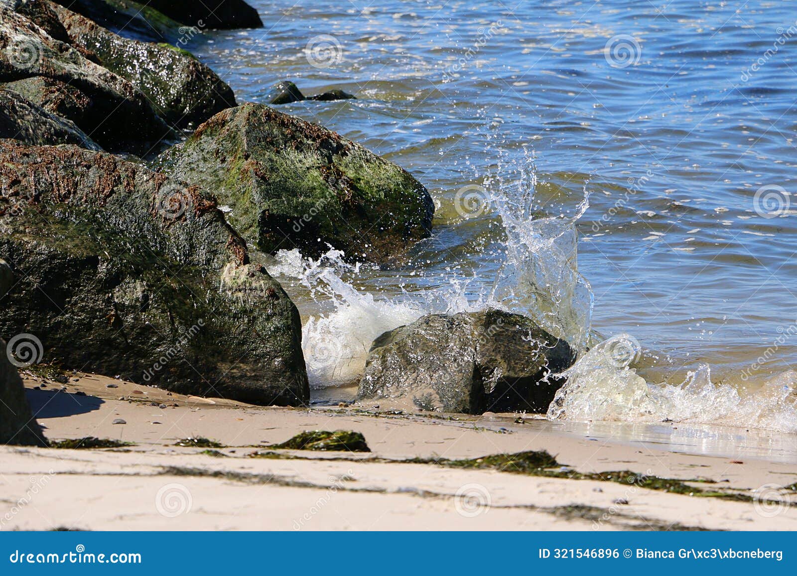 A Wave Splashes Over a Large Stone Lying on the Beach and Splashes in ...
