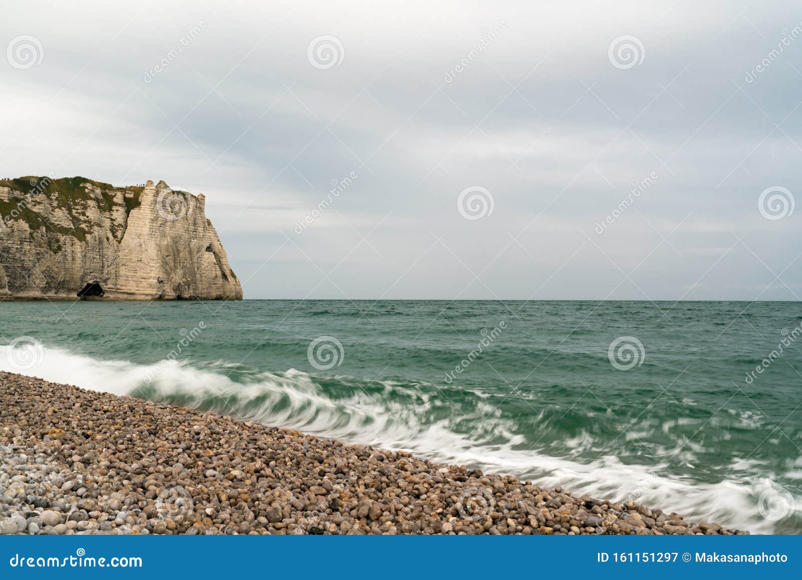 Waves Crash Onto a Rock and Pebble Beach with Jagged Cliffs in the ...
