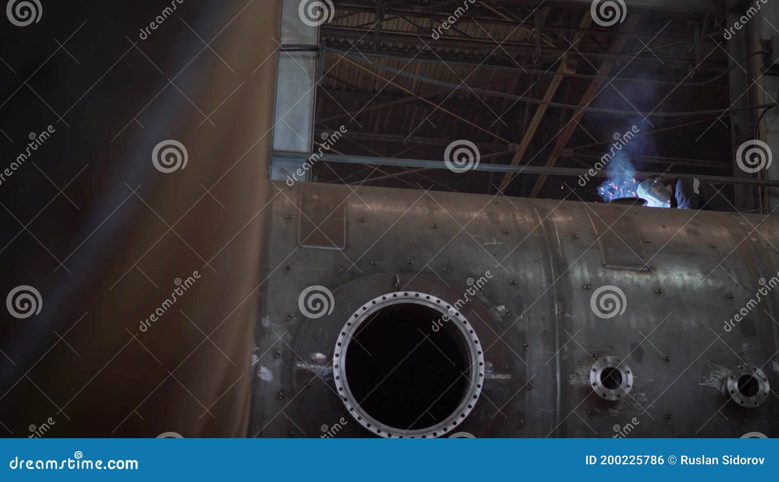 A Welder Welds a Large Pipe in a Factory. a Worker Welding a Pipe ...